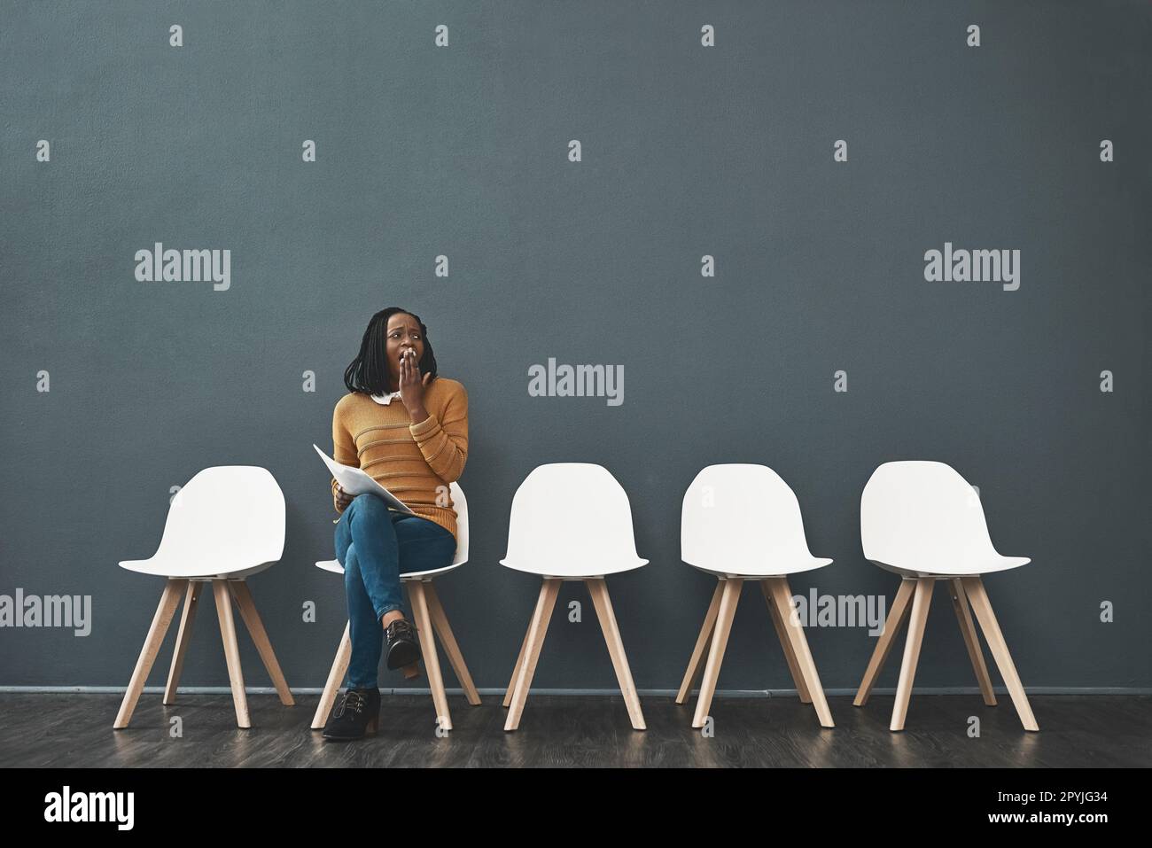 Shes been waiting for a while. a young woman yawning while waiting in ...