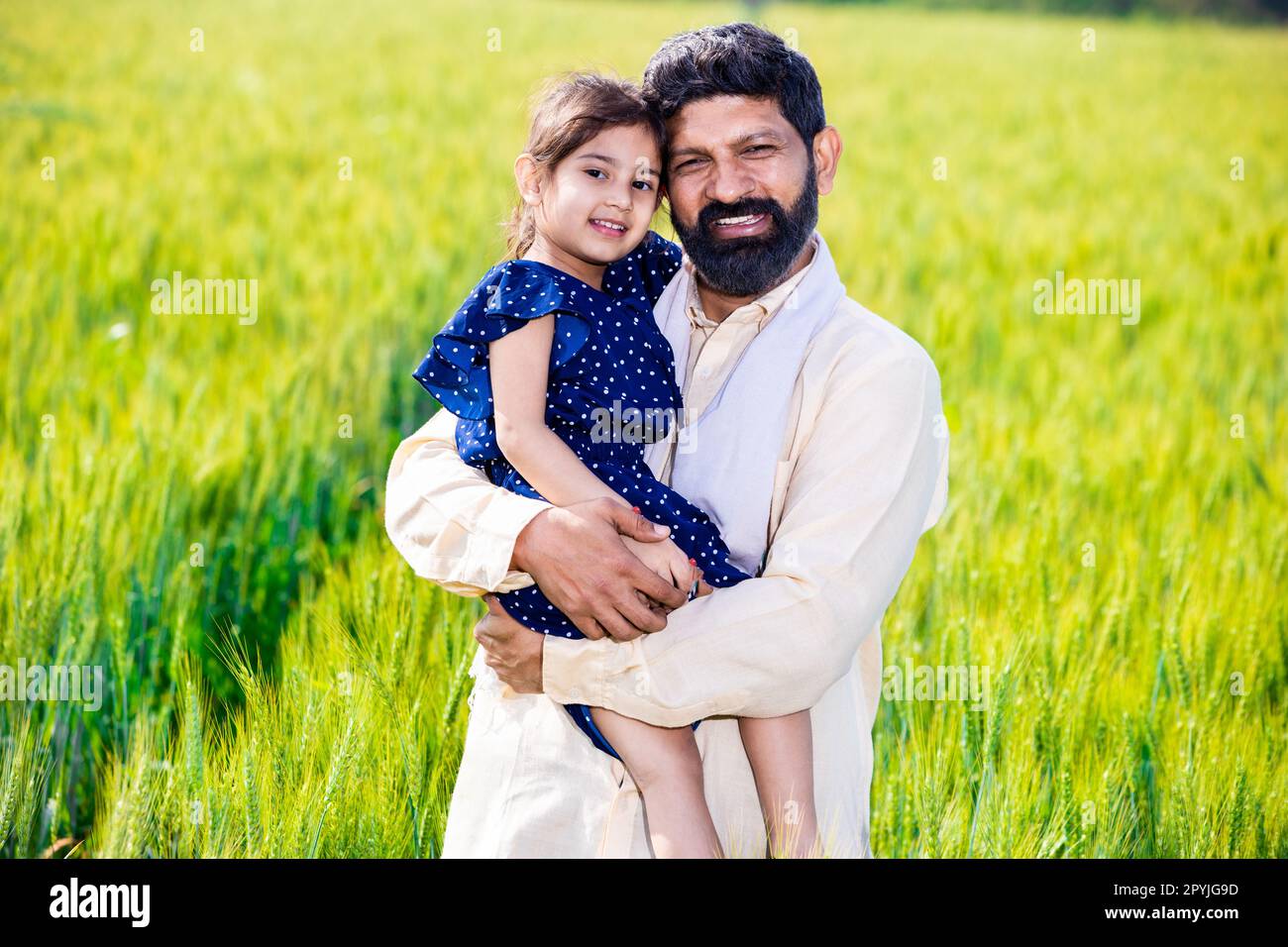 Happy young indian farmer farther daughter standing at wheat ...