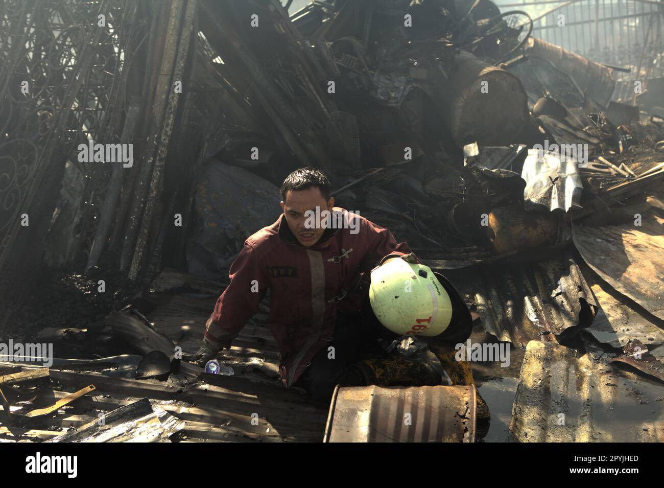 An exhausted firefighter resting between debris after a fire accident ...