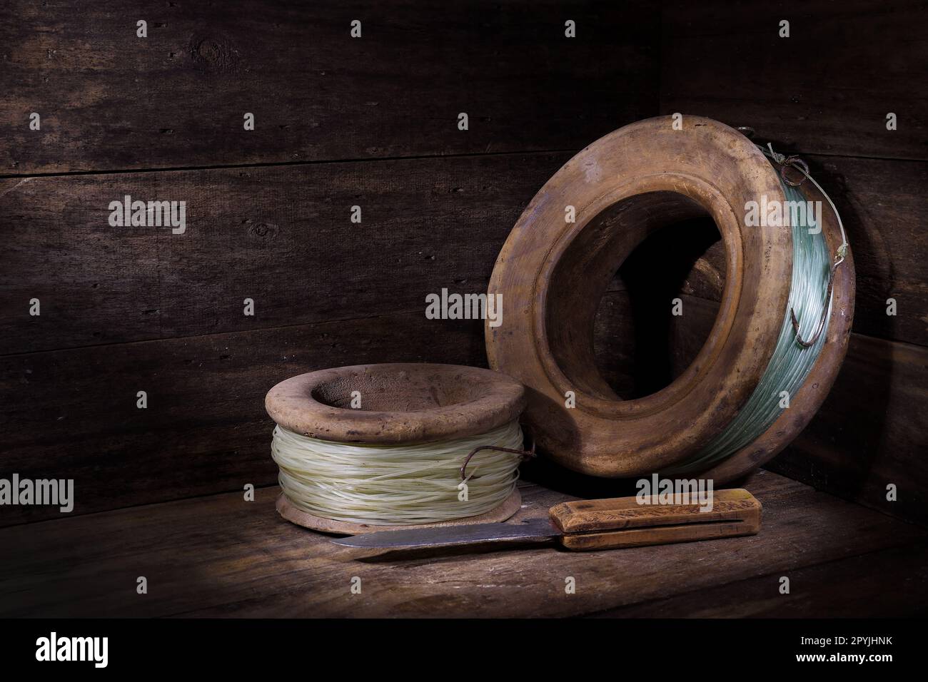 A still life of two old wooden hand fishing reels with lines, rusty ...