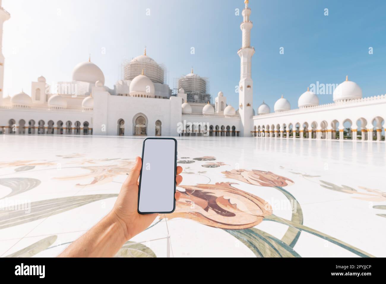Hand with blank screen smartphone and Sheikh Zayed Grand Mosque in Abu ...