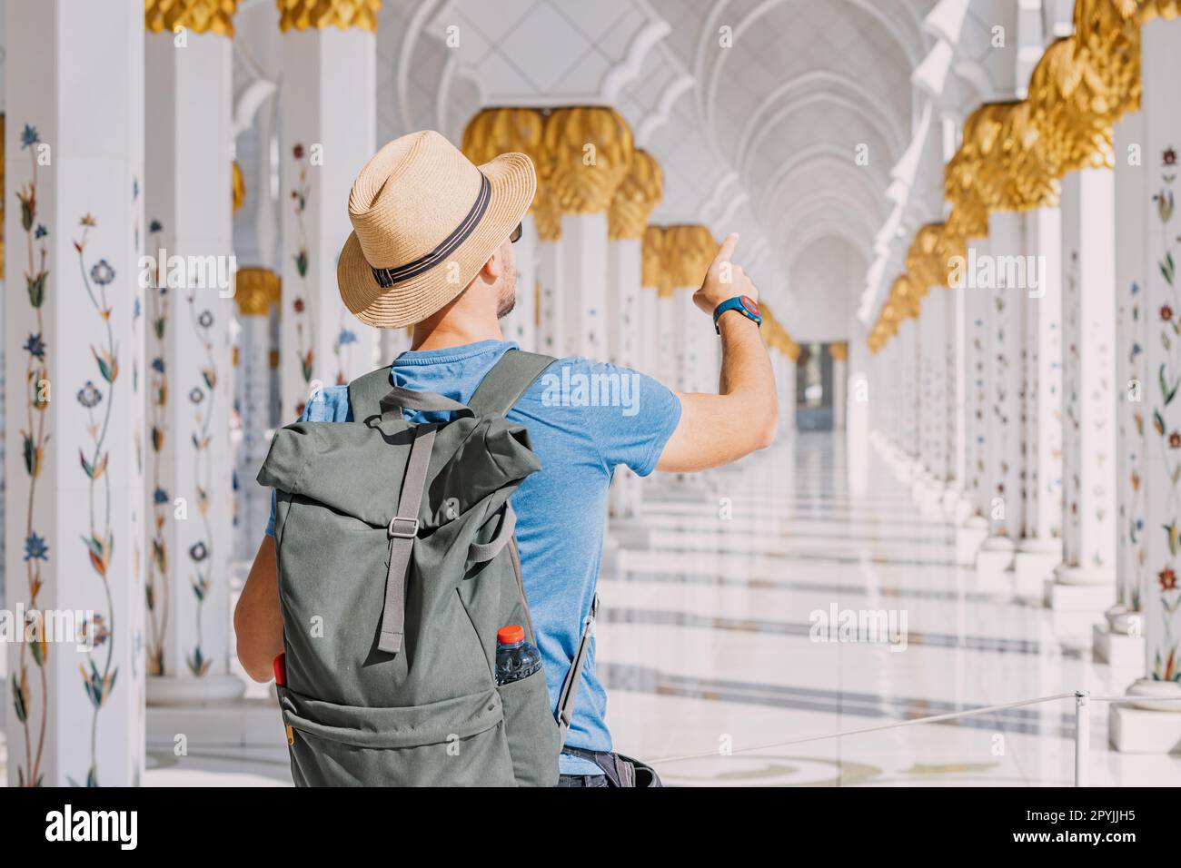 a tourist man in hat with backpack walking through the Great Mosque of ...