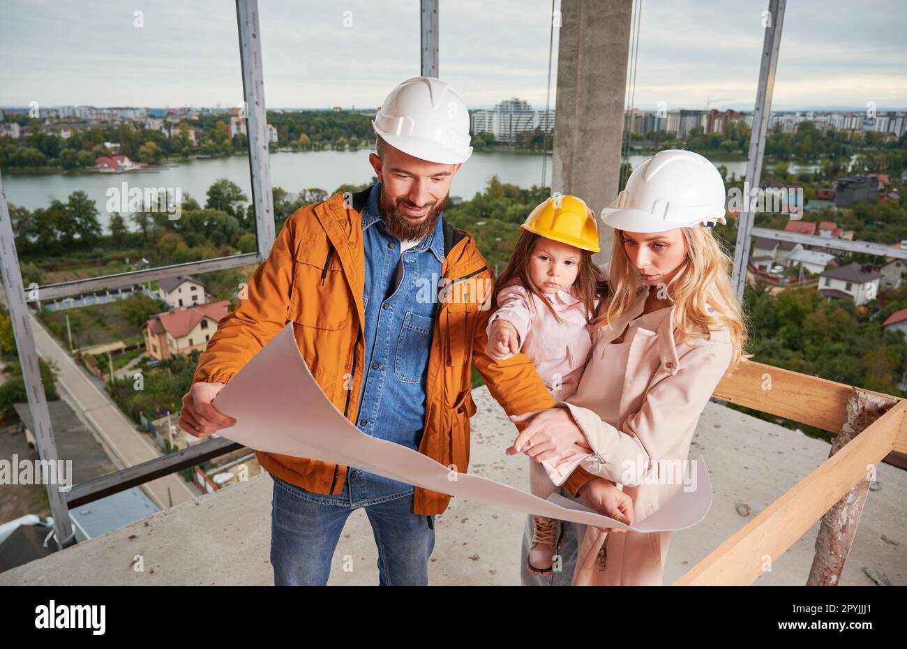 Parents with daughter studying architectural drawings in apartment ...