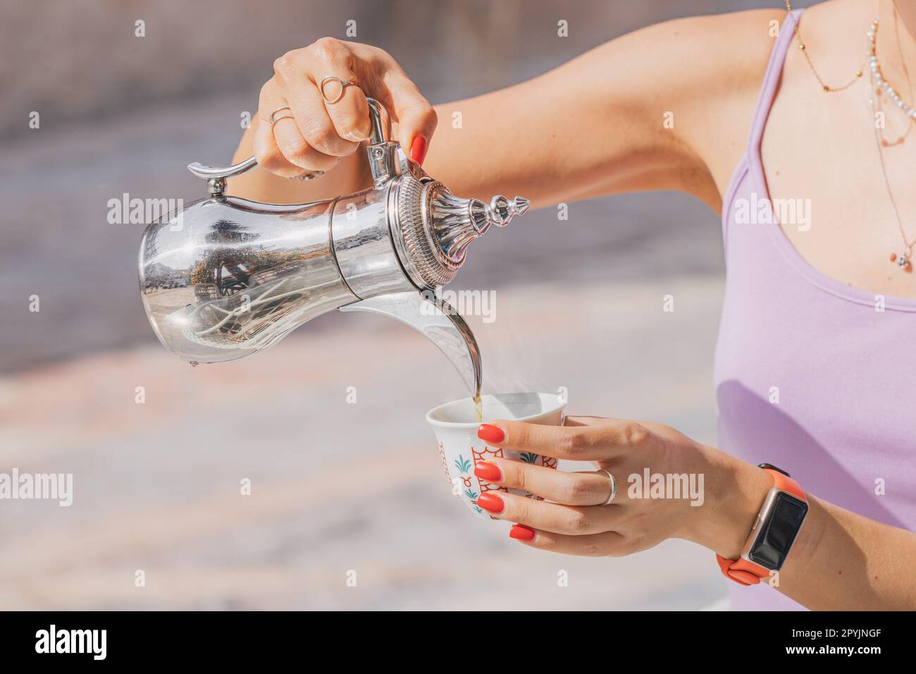Tourist girl pouring fresh coffee from traditional arabic dallah ...