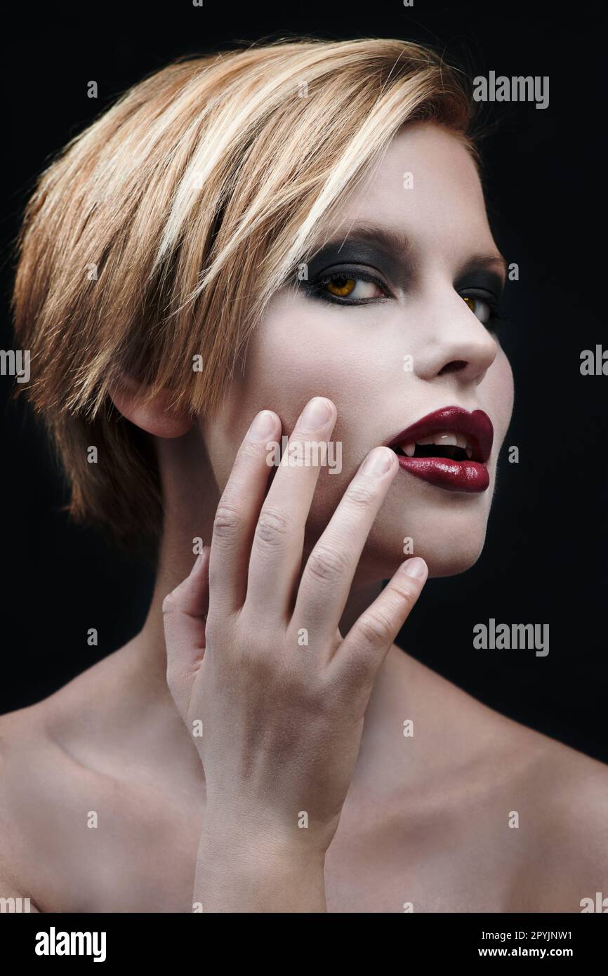 Portrait, hand and a woman vampire in studio on a dark background as a ...