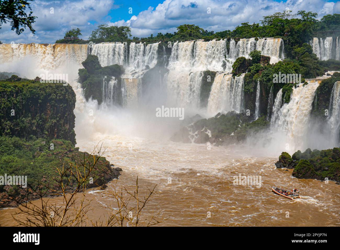 View to cascading water falls, brown river and blue sky, Iguazu Falls ...