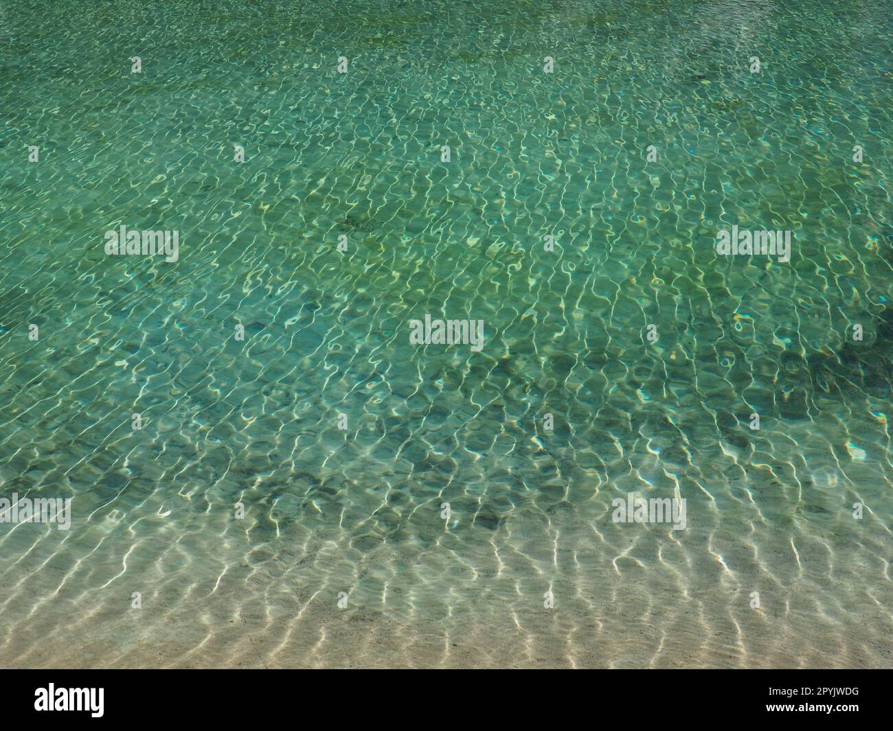 turquoise water. Clear sea water with waves and sun glare. The bottom ...