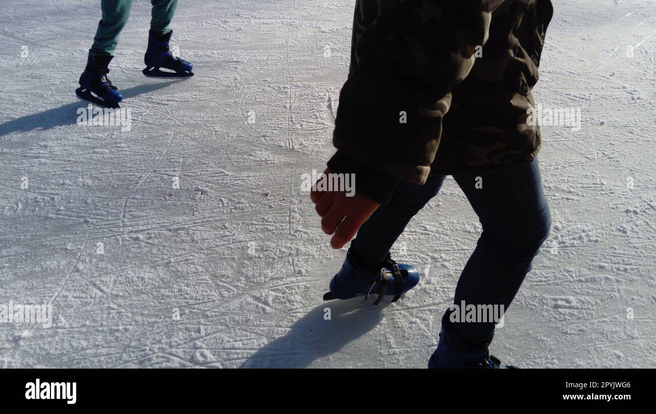 Children ride in a city park at the rink. Legs and hands of a skater ...