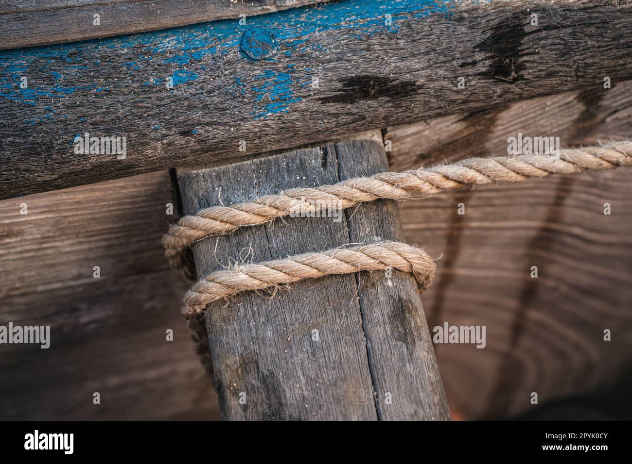 Simple natural rope tied around wooden part of fishing boat, closeup ...