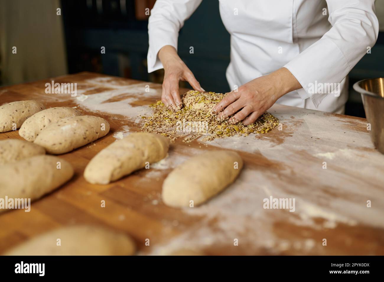 Portrait of positive female baker shaping bread bagels with seeds Stock ...