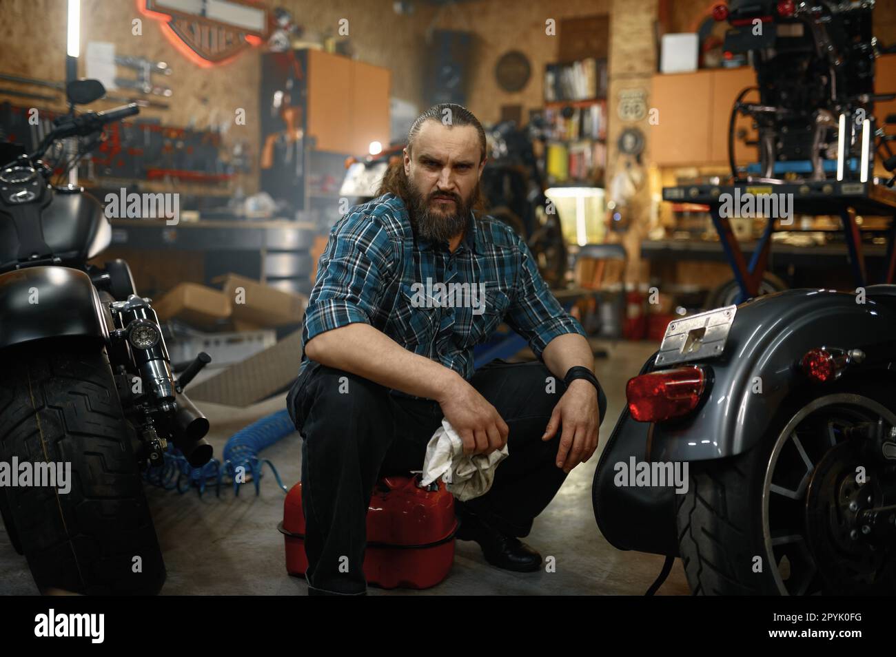Bearded mature man biker cleaning motorcycle in garage workstation ...