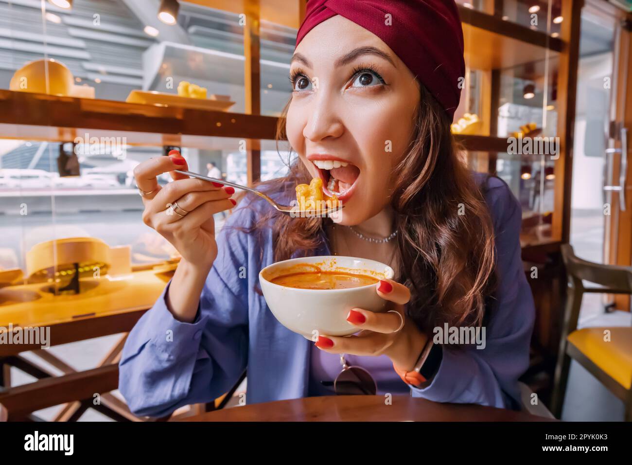 Happy girl eating spicy thai soup Tom Yam in authentic restaurant Stock ...