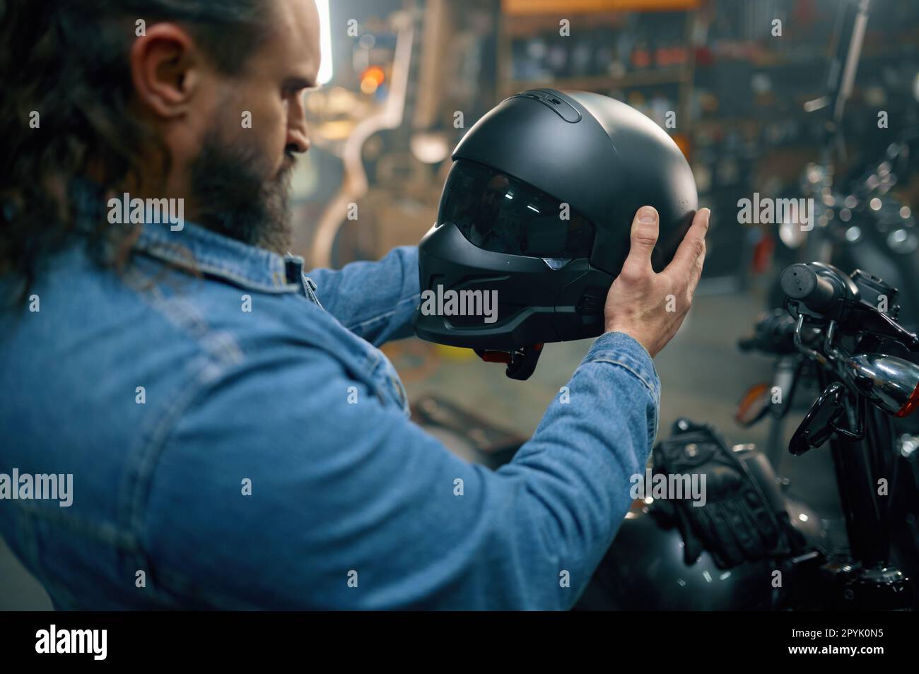 Side view shot on biker choosing new modern safety helmet in motorcycle ...