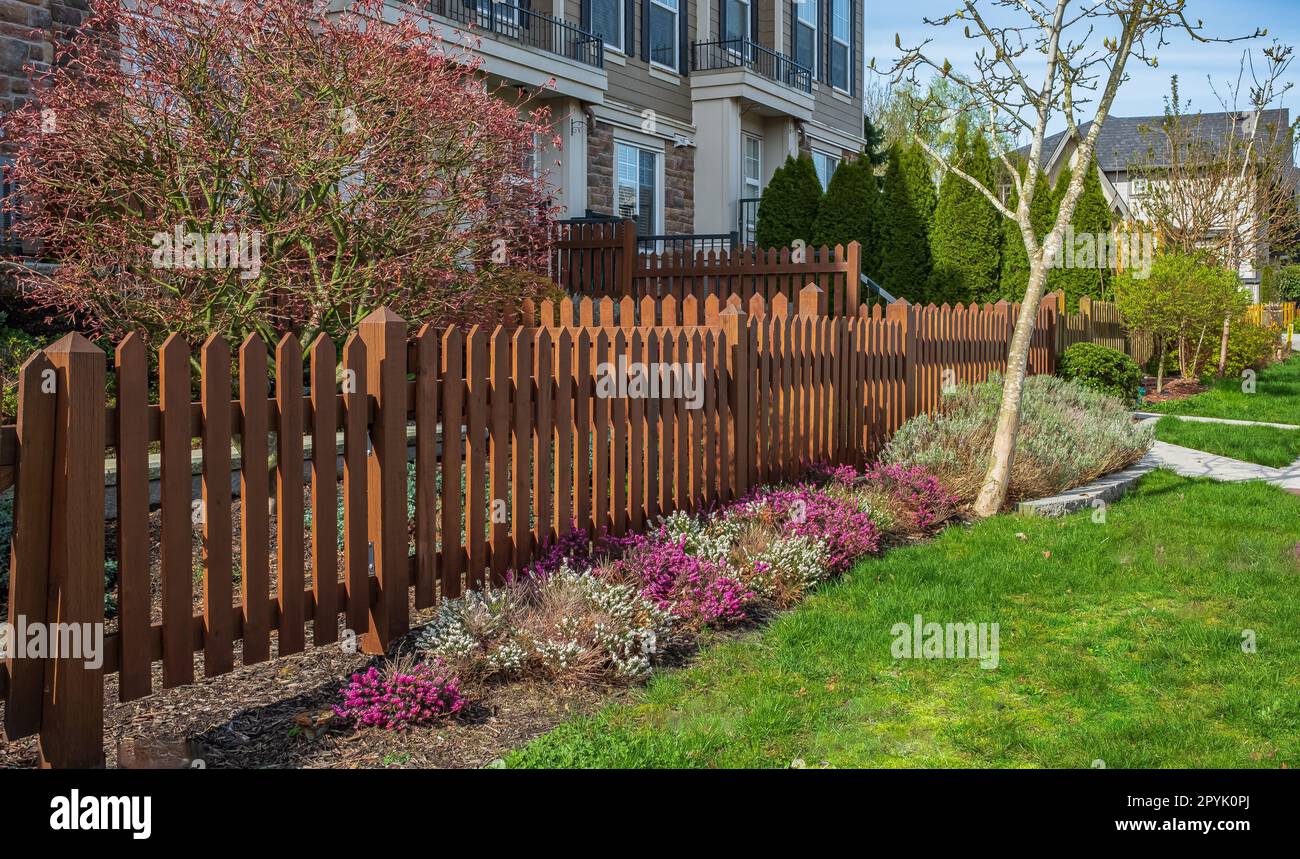 Nice new wooden fence around house. Wooden brown fence with green lawn ...