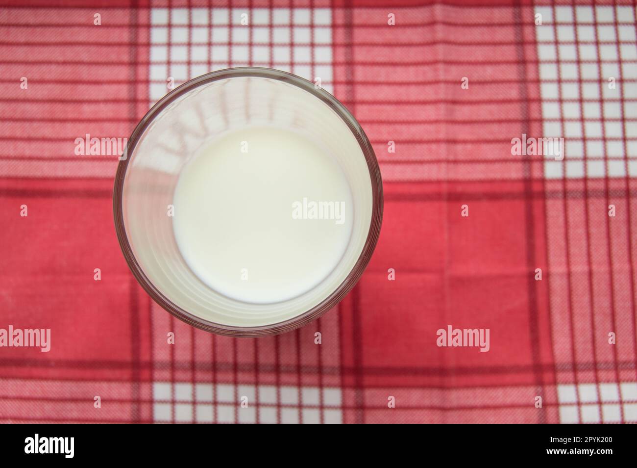 A glass of milk stands on a red checkered cloth, top view Stock Photo ...