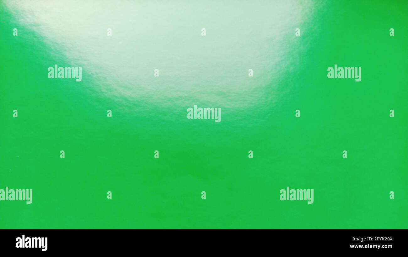 Green sheet of shiny colored paper. The reflective surface glares in ...