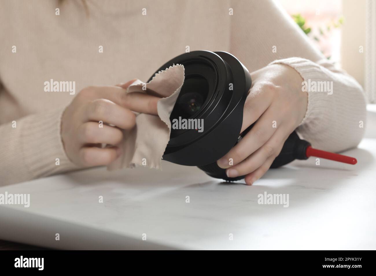 female photographer cleaning dslr fisheye camera lens with microfiber ...