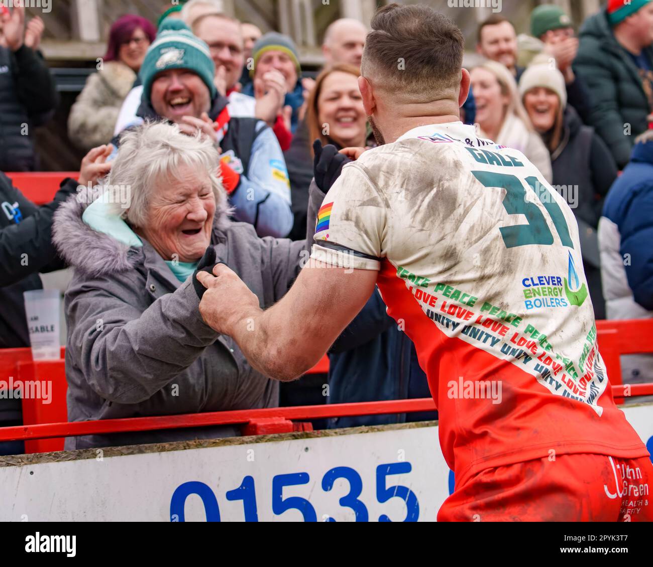 A rugby player stands and shakes hands with a group of people in a ...