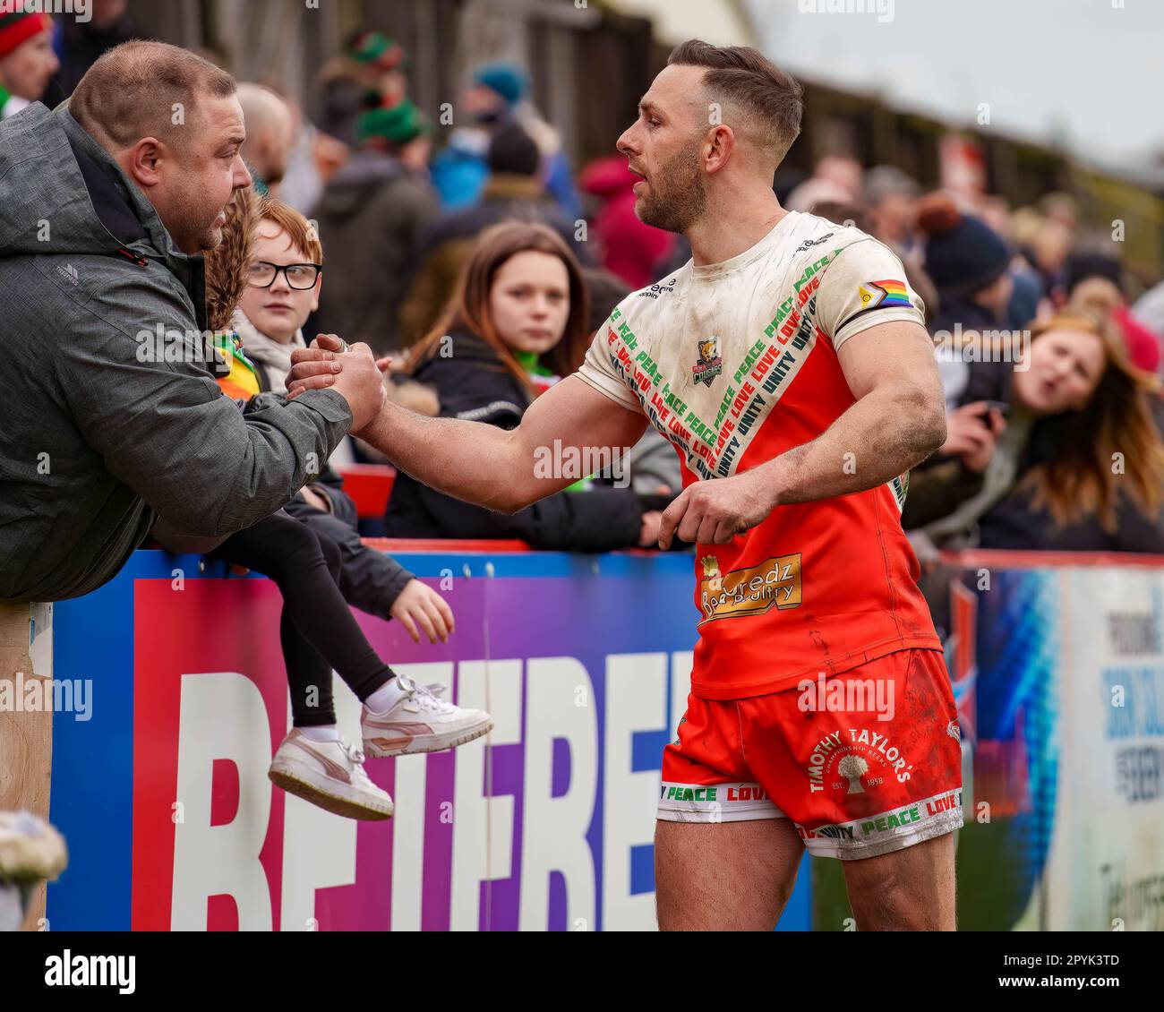 A rugby player stands and shakes hands with a group of people in a ...