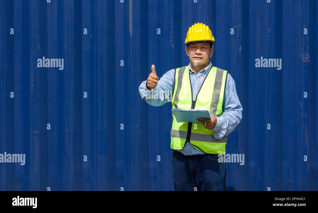 Senior contractor in safety vest and yellow hardhat holding document ...