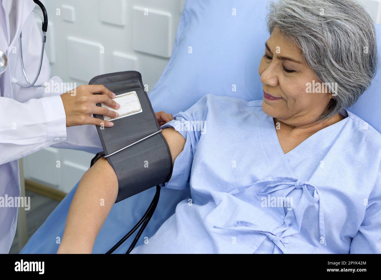 Senior female patient and doctor. Young doctor measures the pressure of an elderly patient in ...