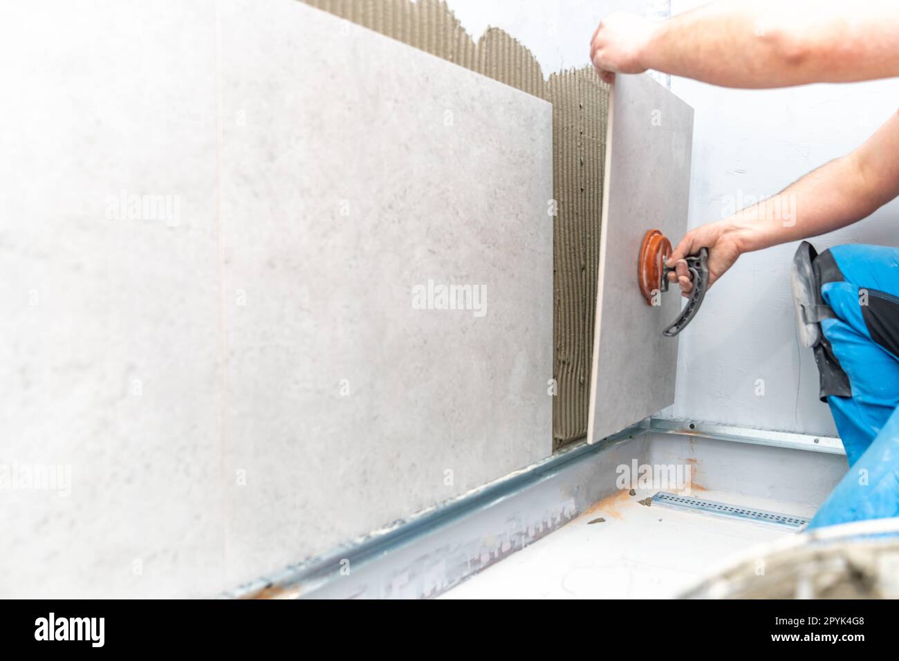 installation of large format tiles on the wall by a craftsman Stock ...