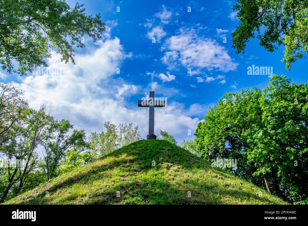 Christian cross on a mound against a blue sky with white clouds Stock ...