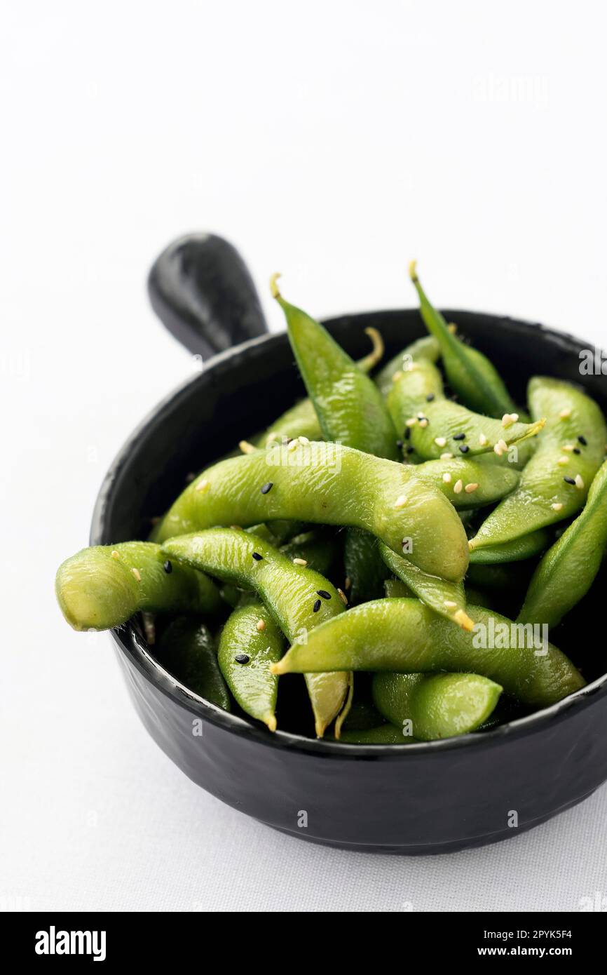 japanese edamame beans snack in black ceramic bowl on white background ...