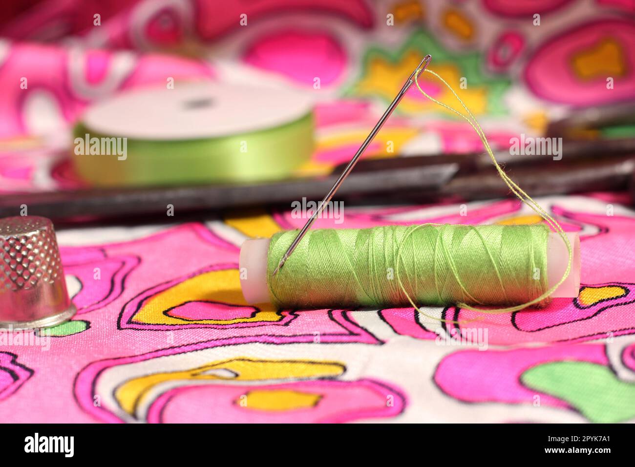 Spool of Green Thread, Thimble and Needle on Retro Pink and Green ...