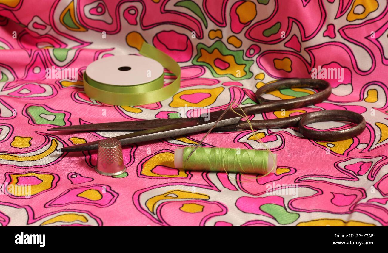 Spool of Green Thread, Thimble and Needle on Retro Pink and Green ...