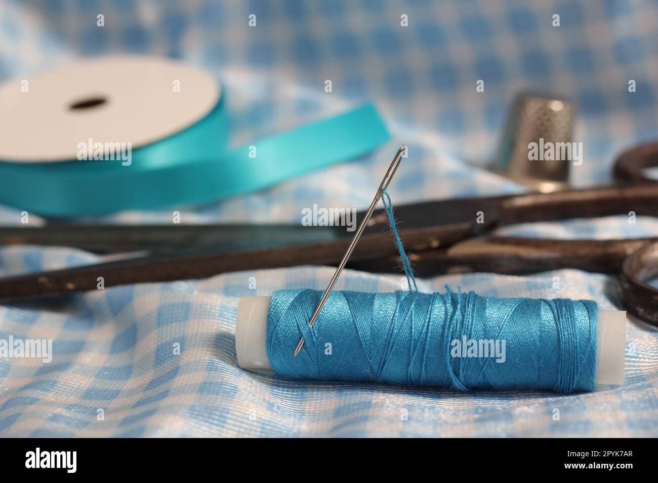 Spool of Blue Thread, Thimble and Needle on Blue and White Fabric Stock ...
