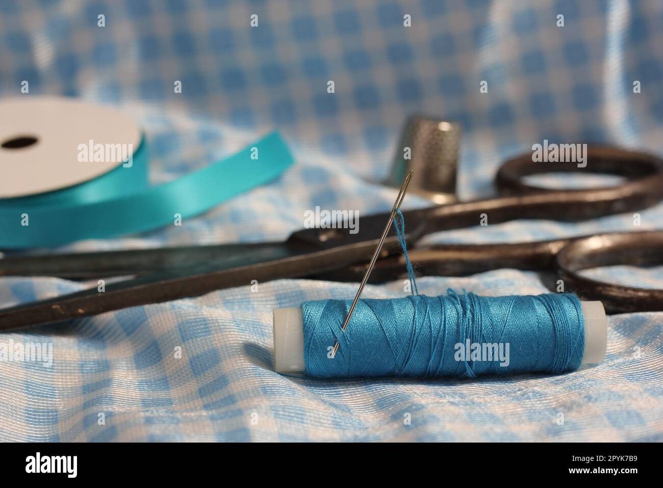 Spool of Blue Thread, Thimble and Needle on Blue and White Fabric Stock ...