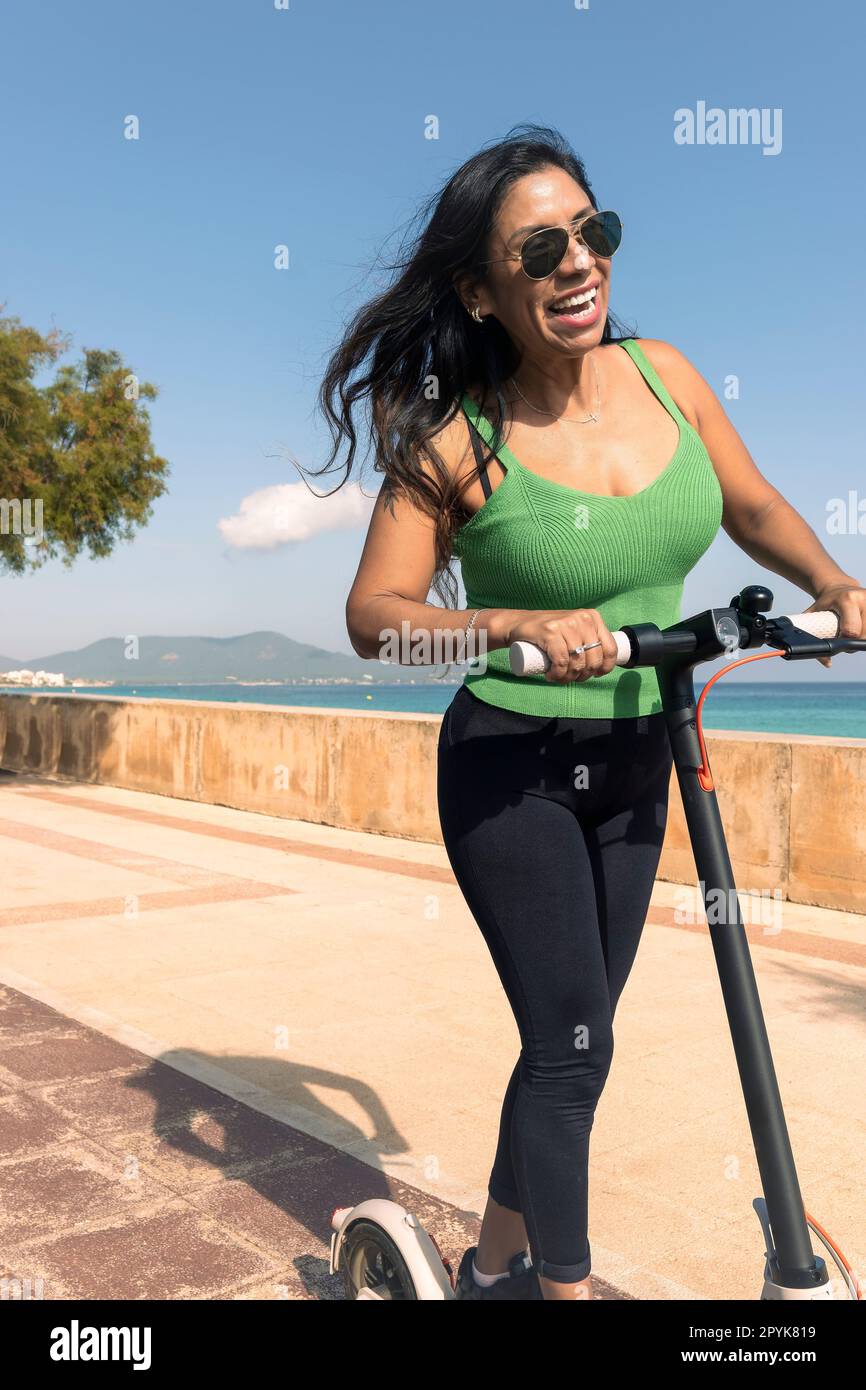 Woman riding electric scooter, happy and summer ride at tropical island ...