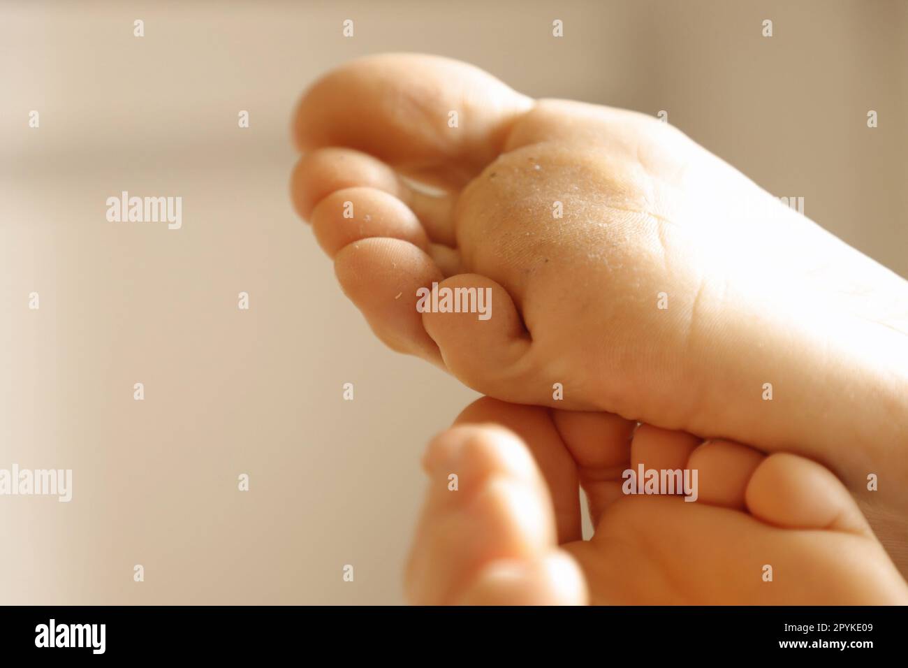 Close-up of a mother and child's feet in a tender moment, illuminated ...