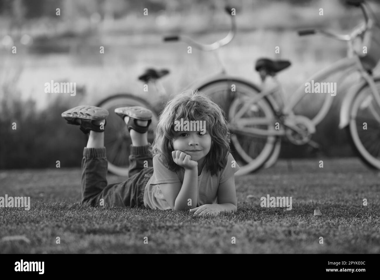 Happy smiling child boy relaxing on the grass. Cute kid boy enjoying on ...