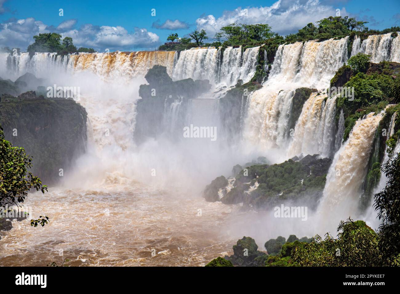 Panoramic view to cascading water falls, brown river and blue sky ...