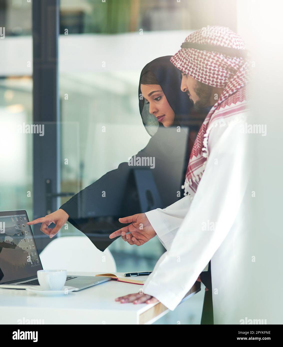 Corporate collaboration in action. two muslim coworkers using a laptop ...