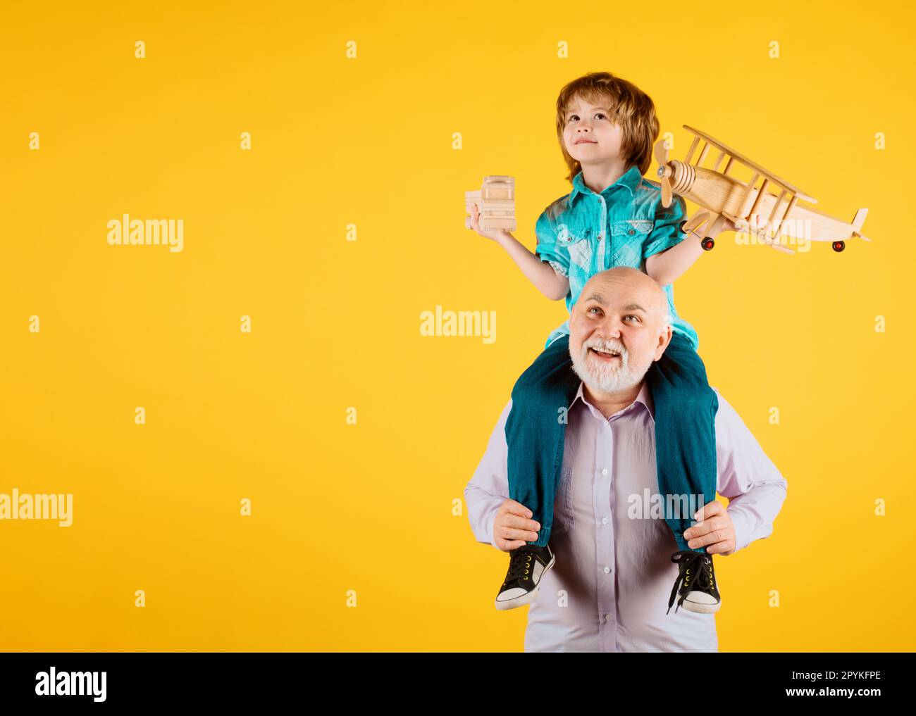 Grandfather and son piggyback ride with plane and wooden toy truck. Men ...