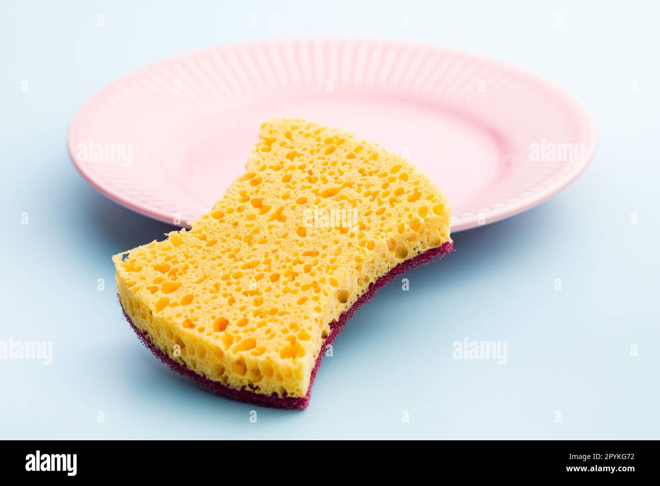 Sponge for washing dishes on the plate on blue background Stock Photo ...
