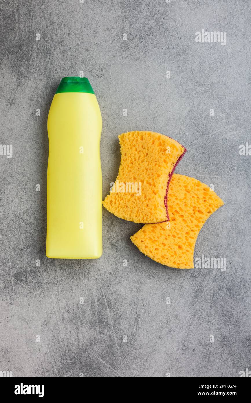 Sponge for washing dishes, plastic bottle and plates on the gray ...