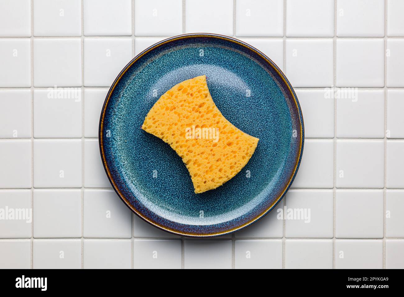 Sponge for washing dishes on the plate on tiles. Top view Stock Photo ...