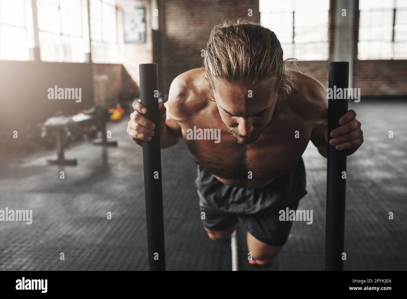 It takes power and perseverance. a muscular young man pushing a weight ...