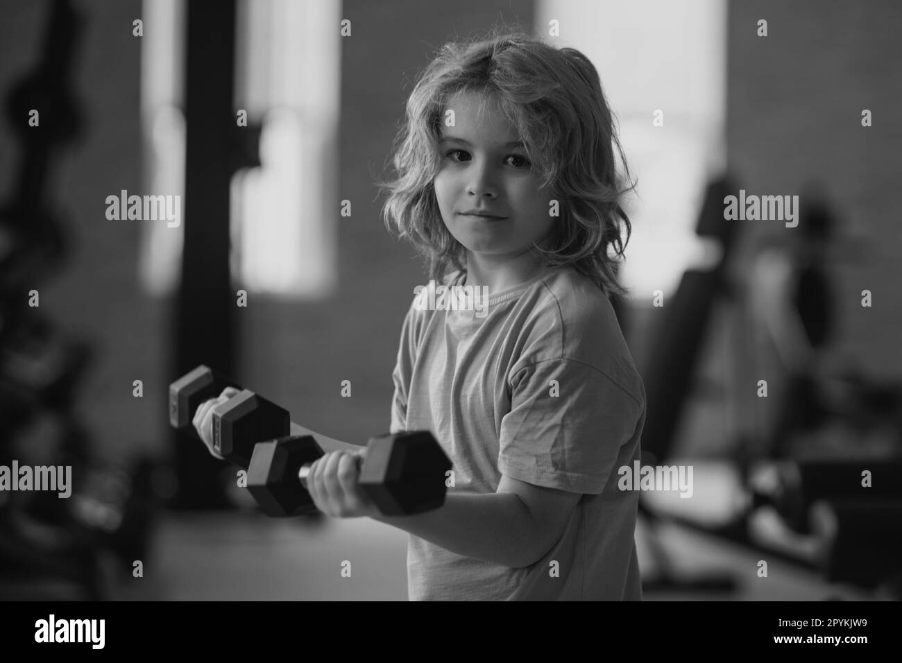 Kid workout kid in gym. Sport activities at leisure with children. Blonde boy holding dumbbells ...