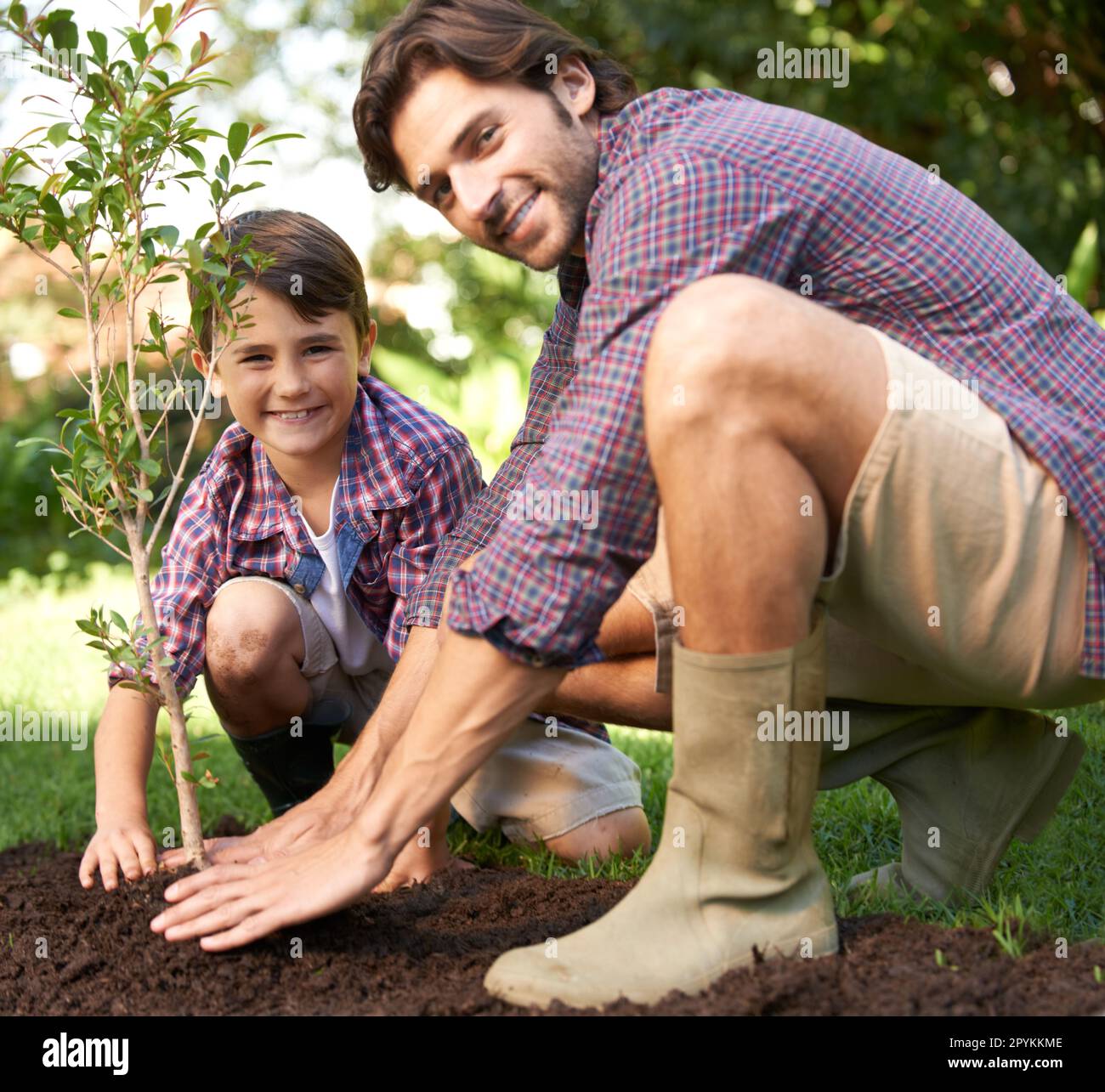 Portrait, father and child planting a tree together for sustainability ...