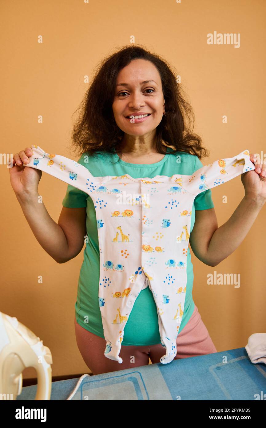 Latin American adult pregnant woman smiles and shows at camera a cute ...