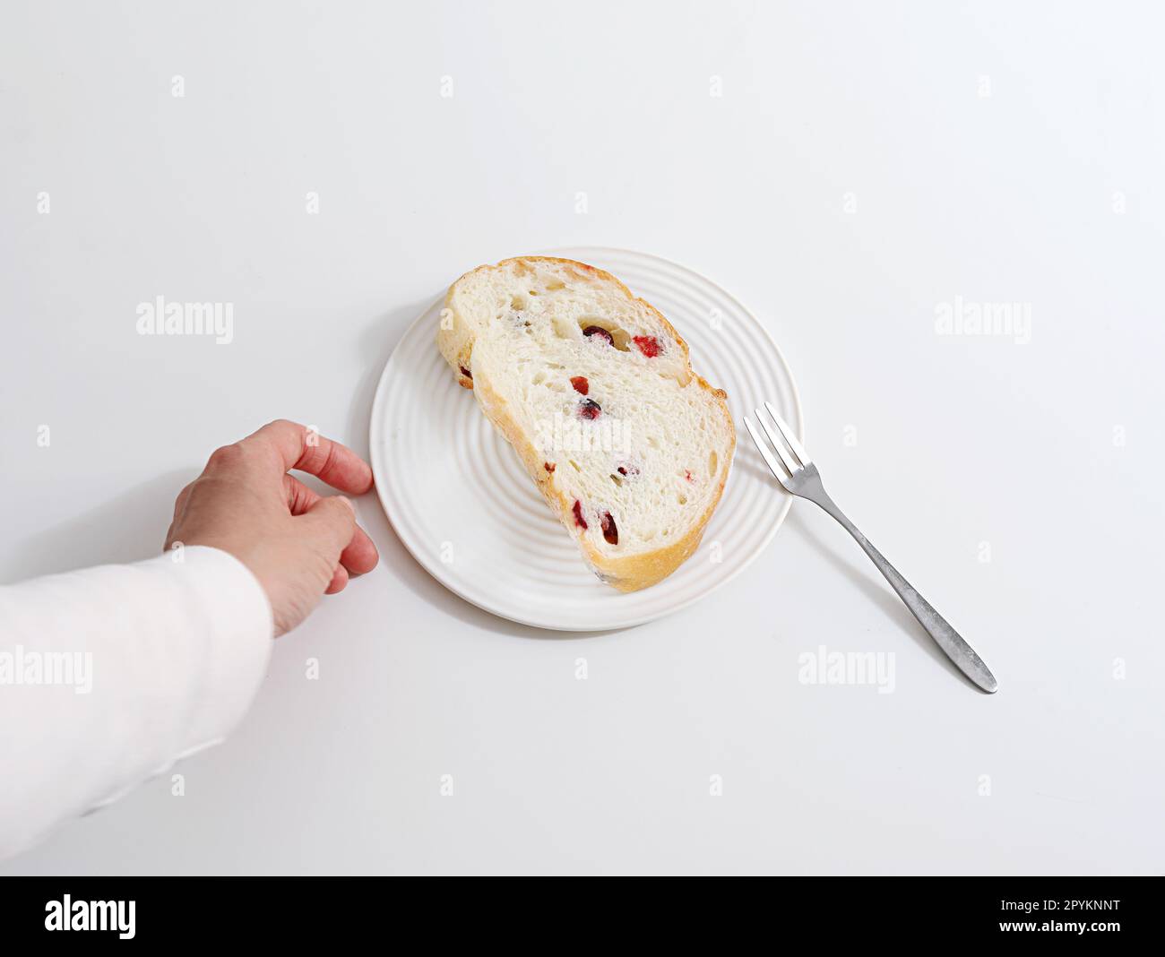 A hand reaching for a piece of bread on a plate Stock Photo - Alamy