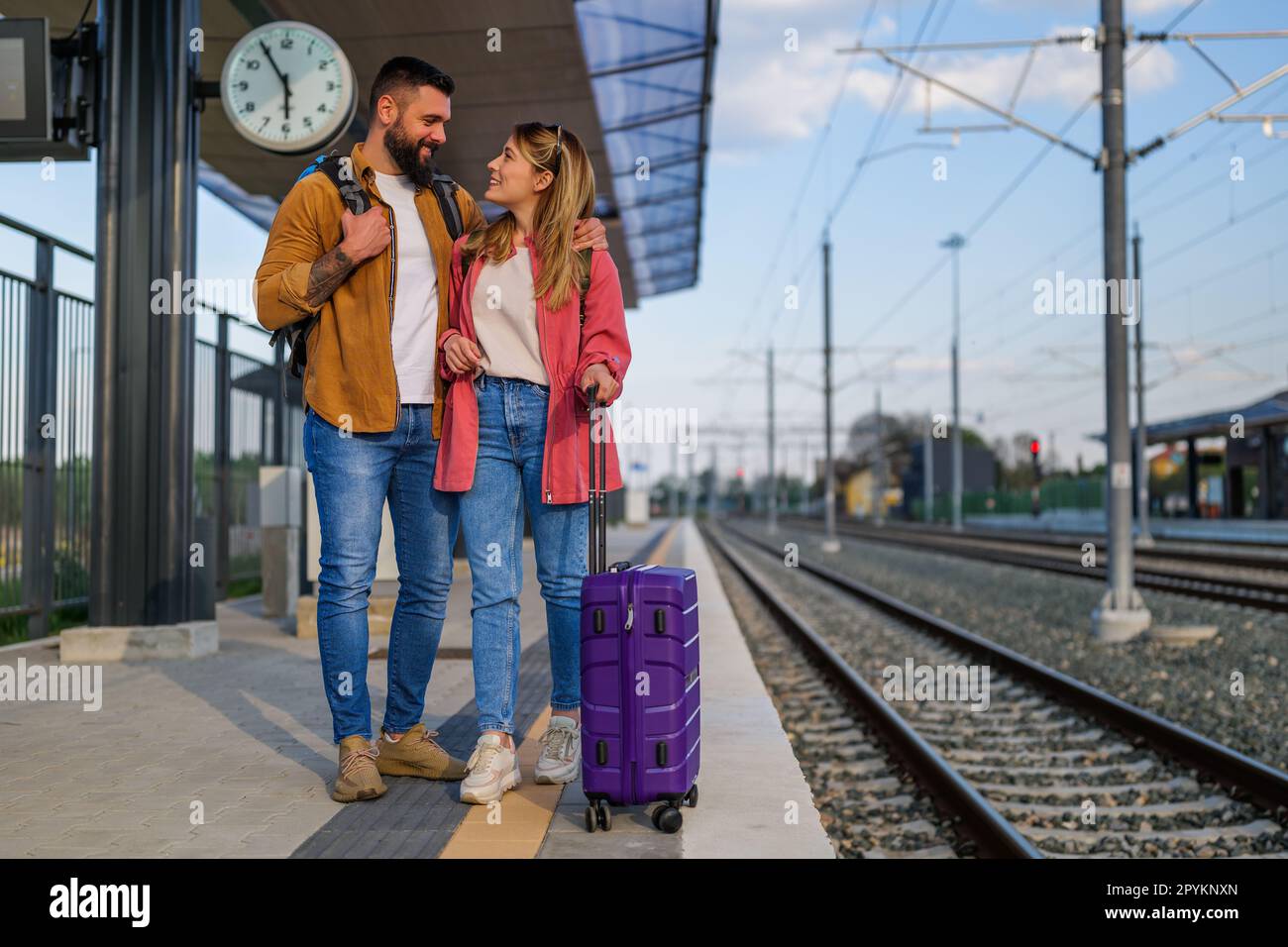 Happy couple is standing at railway station and waiting for arrival of their train Stock Photo ...