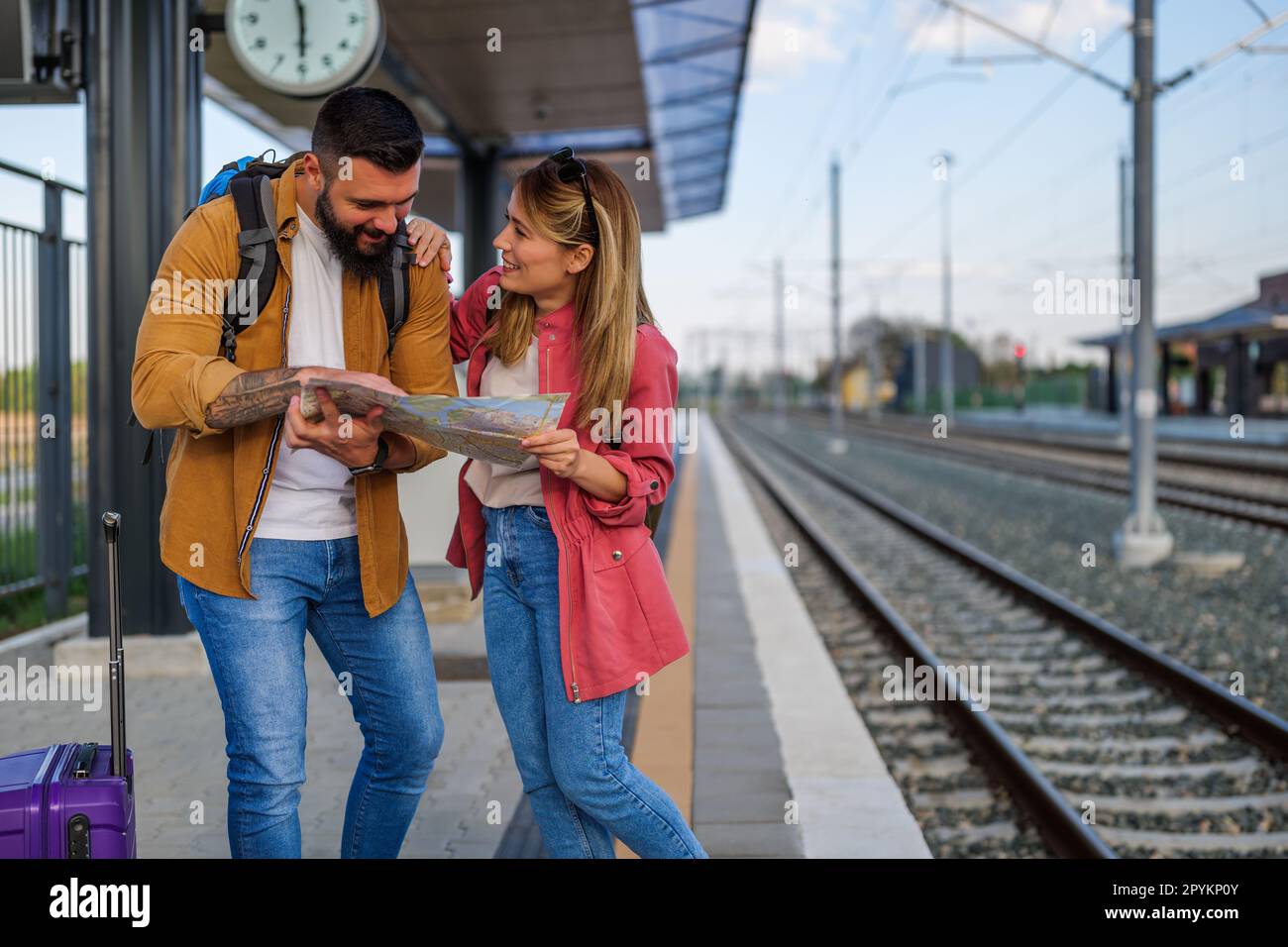 Happy couple is standing at railway station and waiting for arrival of ...