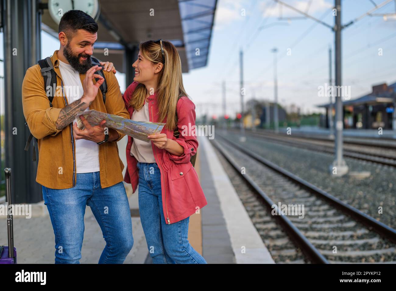 Happy couple is standing at railway station and waiting for arrival of ...