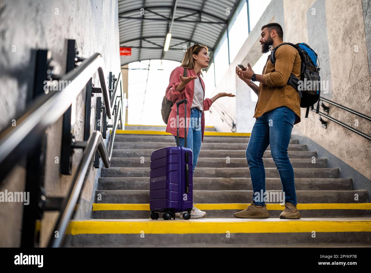 Adult couple missed the departure of the train. The are arguing at at ...